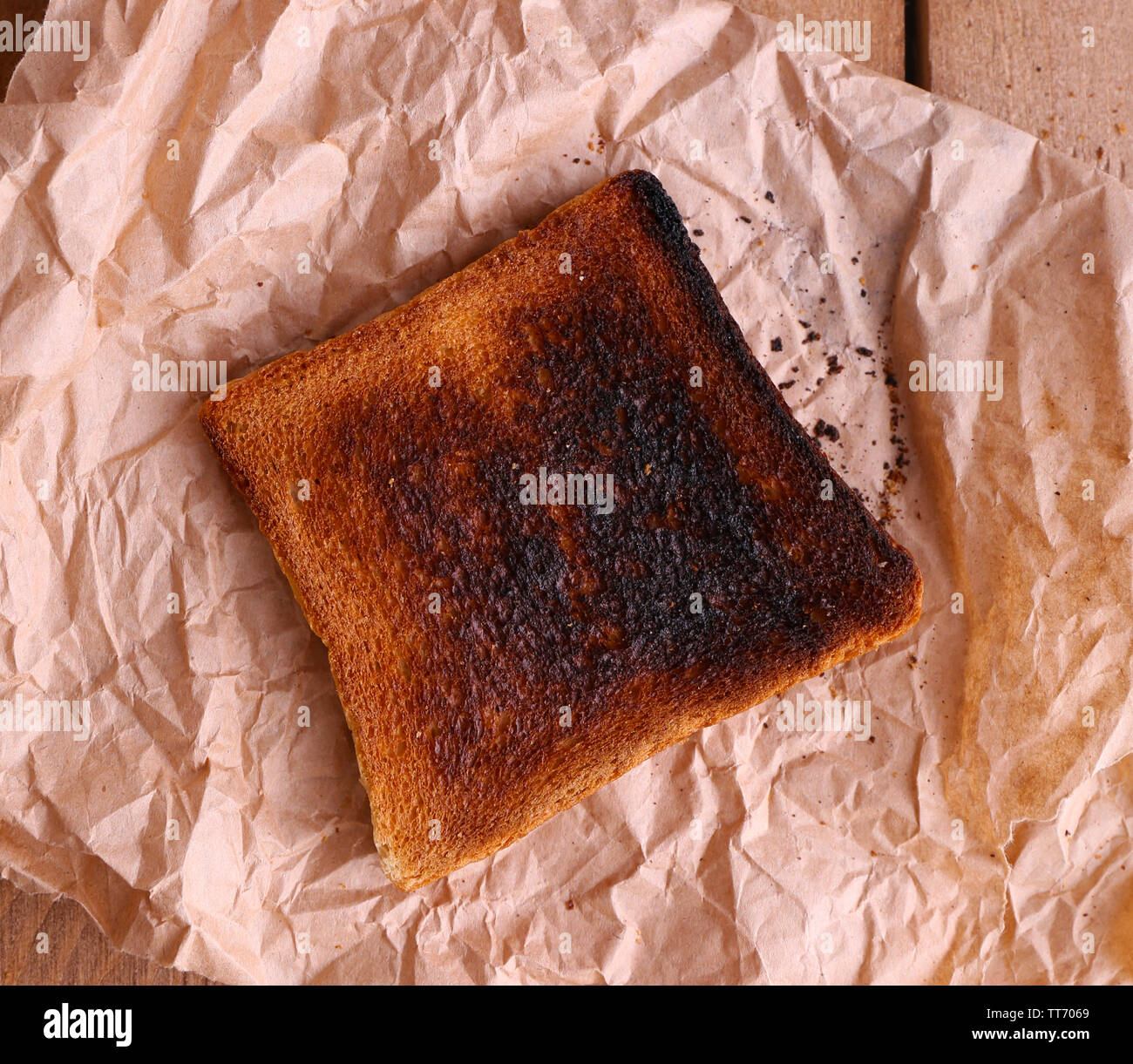 Burnt toasted bread on piece of paper and wooden table background Stock ...