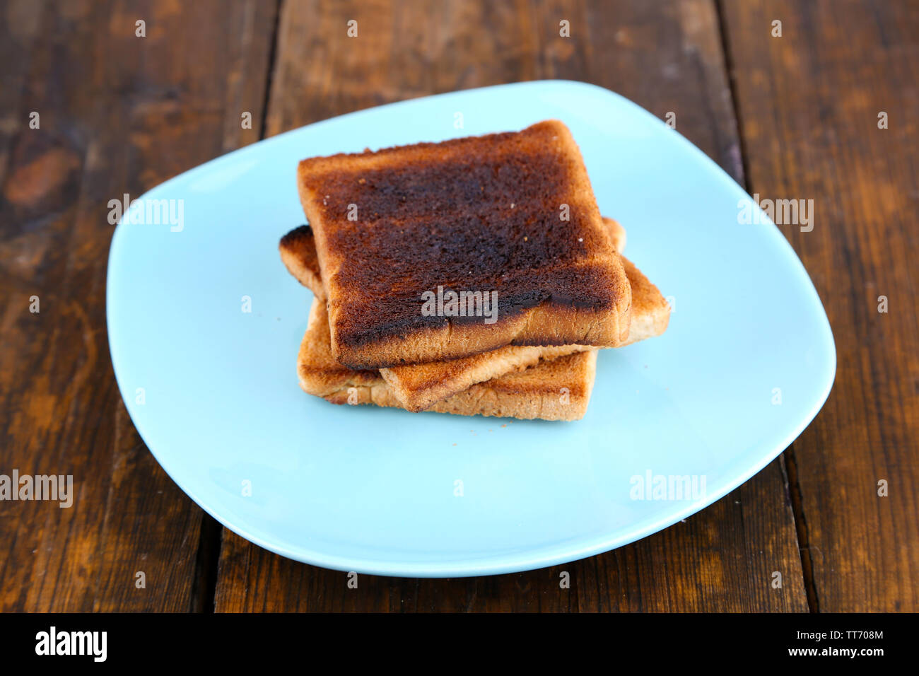 Burnt toast bread on turquoise plate, on wooden table background Stock ...