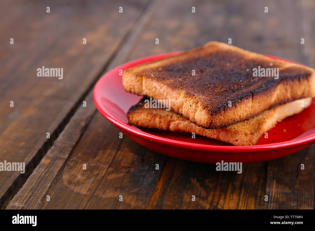 Burnt toast bread on red plate, on wooden table background Stock Photo ...