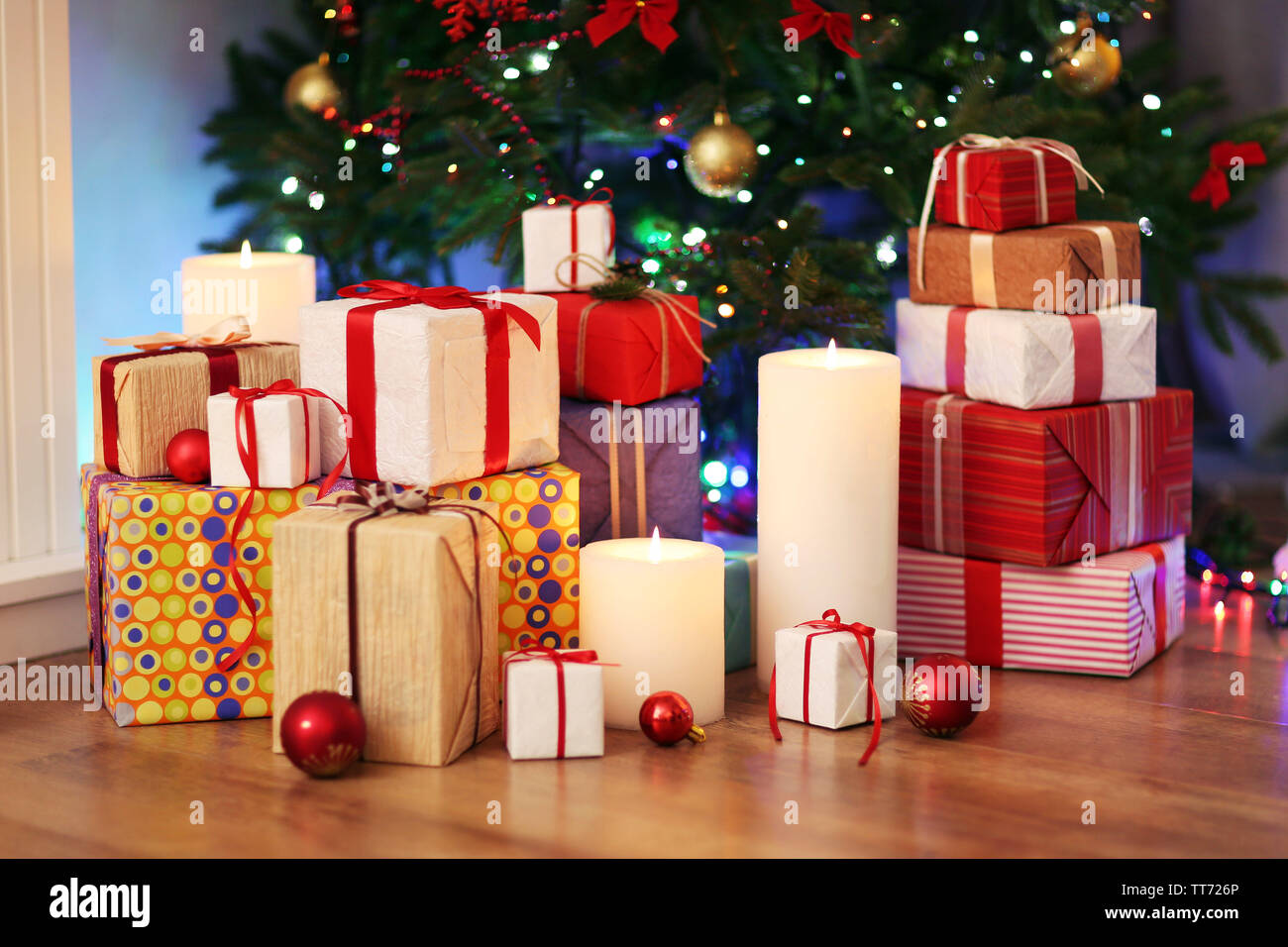 Pile of present boxes under Christmas tree on wooden floor, indoors ...