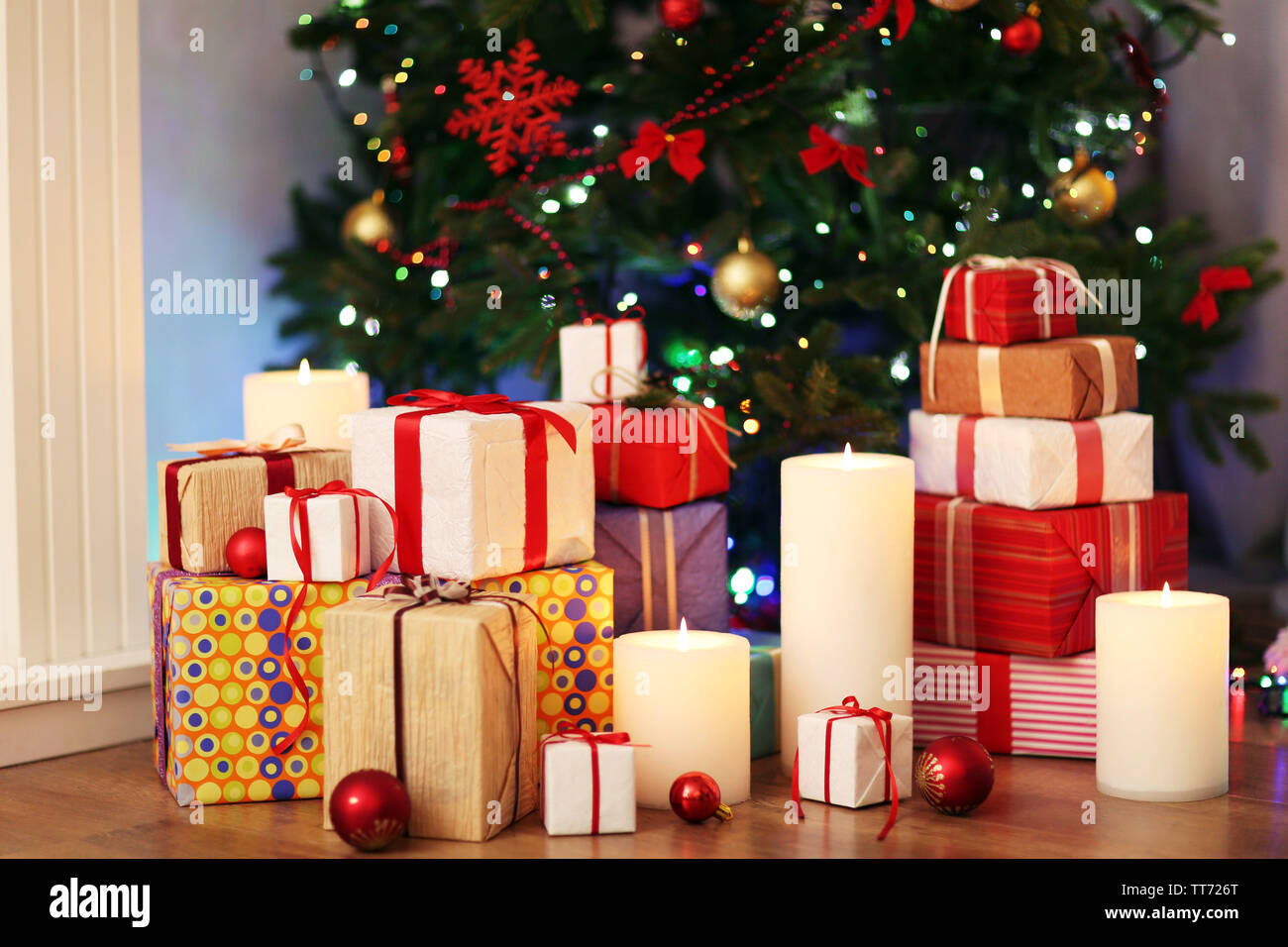 Pile of present boxes under Christmas tree on wooden floor, indoors ...