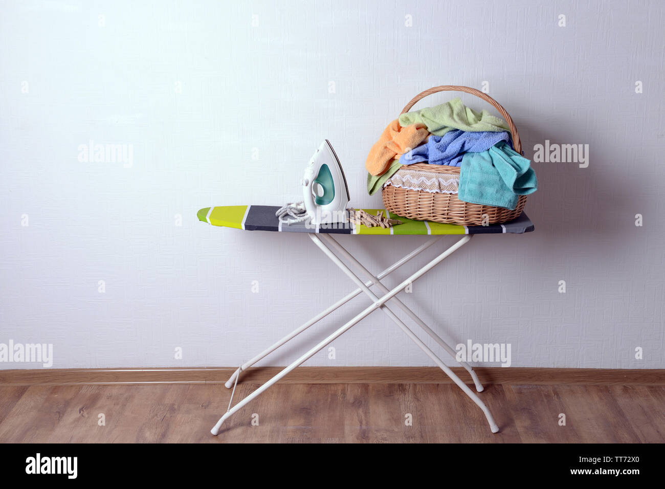 Ironing board with laundry on light background Stock Photo - Alamy
