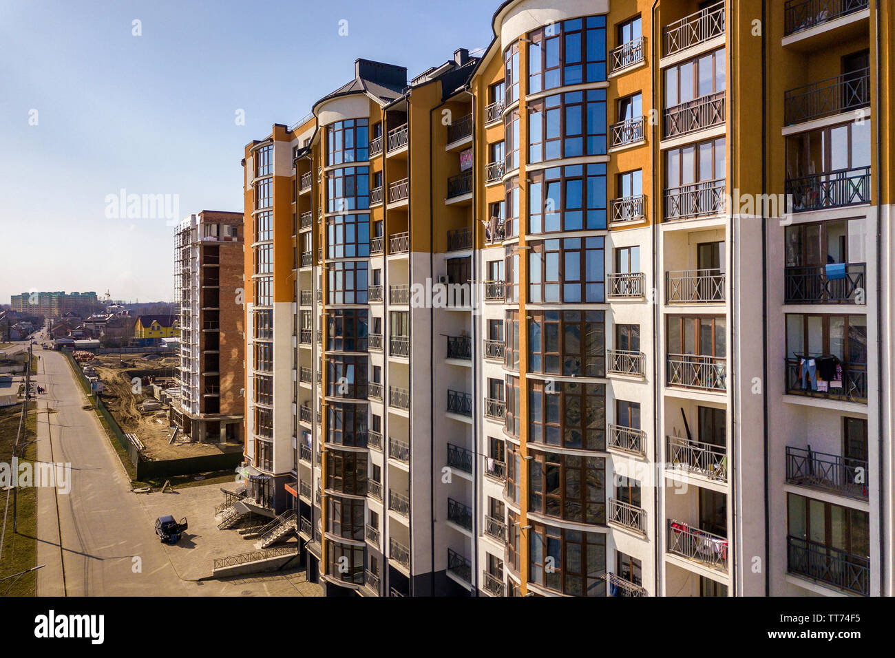 New tall apartment buildings and parked cars and suburb houses on blue ...
