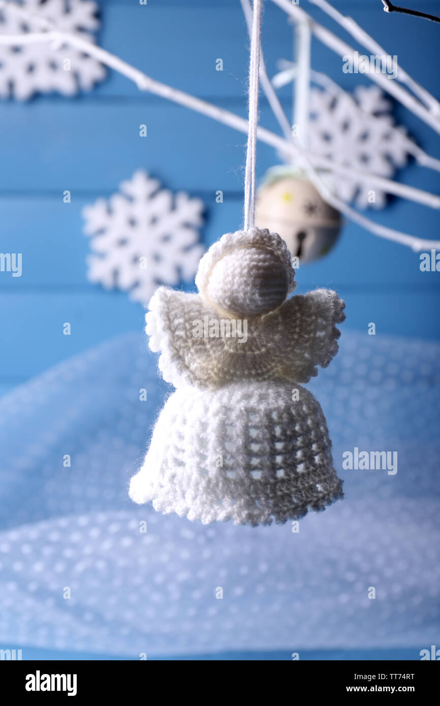 Knitted Christmas angel hanging on bud on color wooden background Stock ...