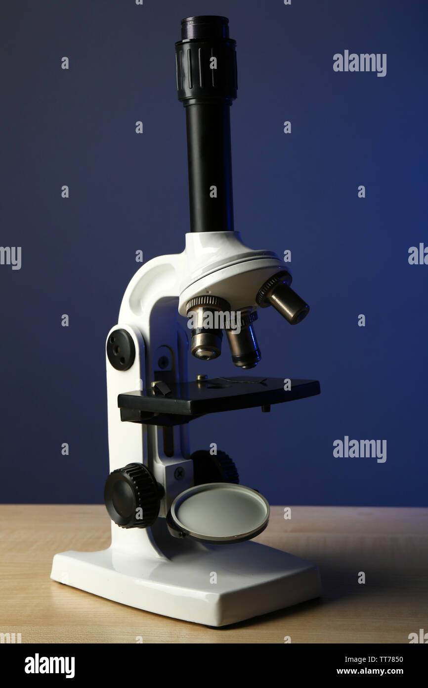Microscope on table, on color background Stock Photo - Alamy