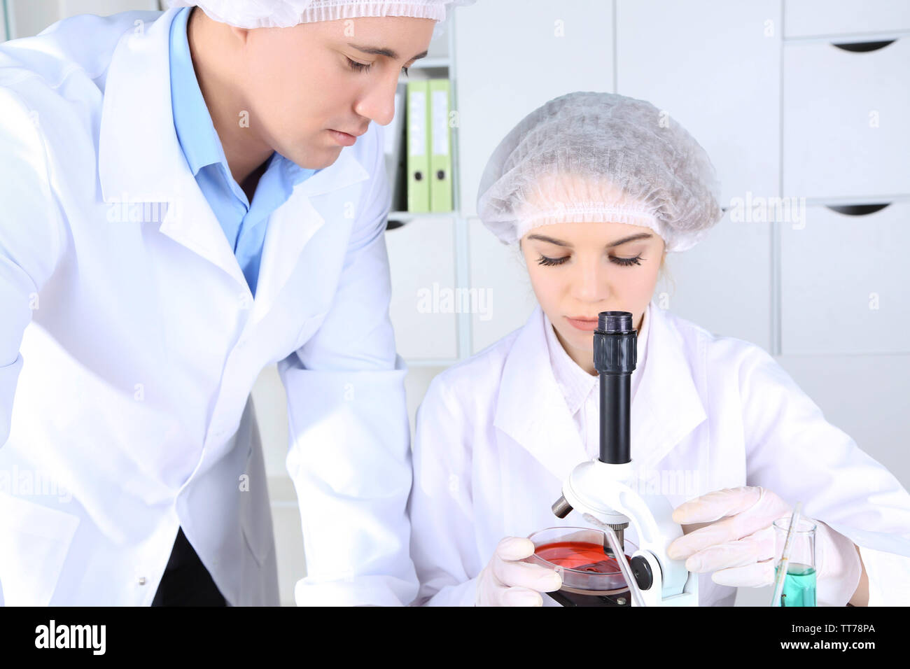 Male and female scientists with microscope in laboratory Stock Photo ...