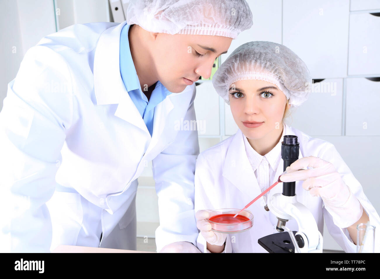 Male and female scientists with microscope in laboratory Stock Photo ...