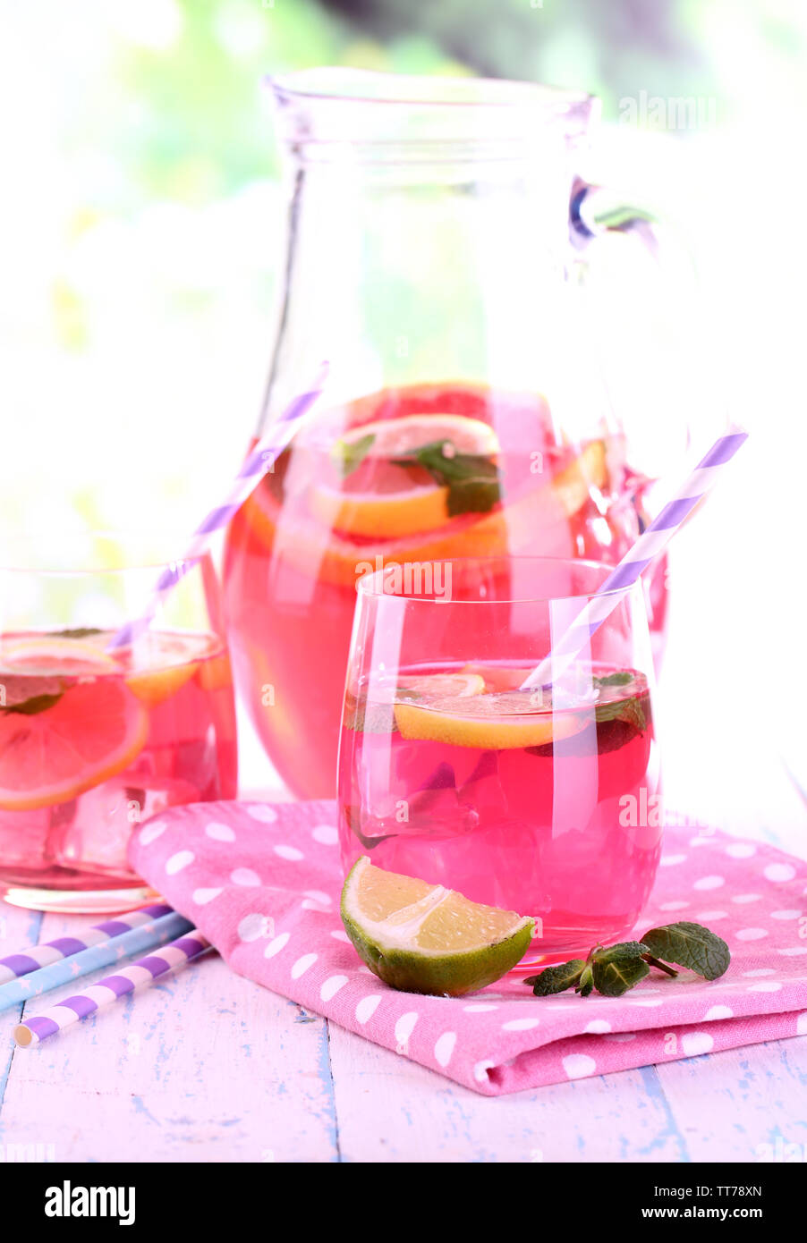 Pink lemonade in glasses and pitcher on table on natural background ...
