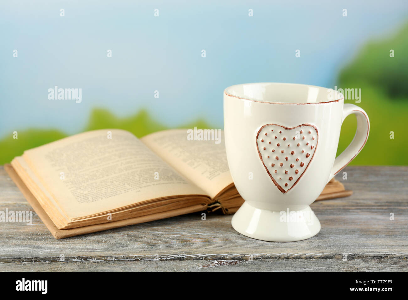 Cup and book on table, on bright background Stock Photo - Alamy