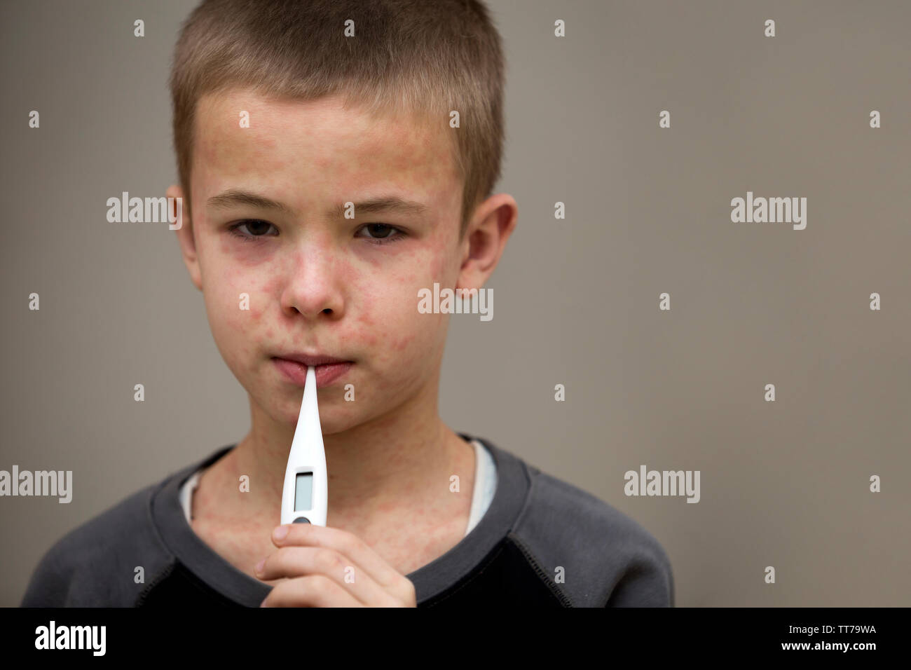 Portrait of sick sad boy child with thermometer having fever suffering ...