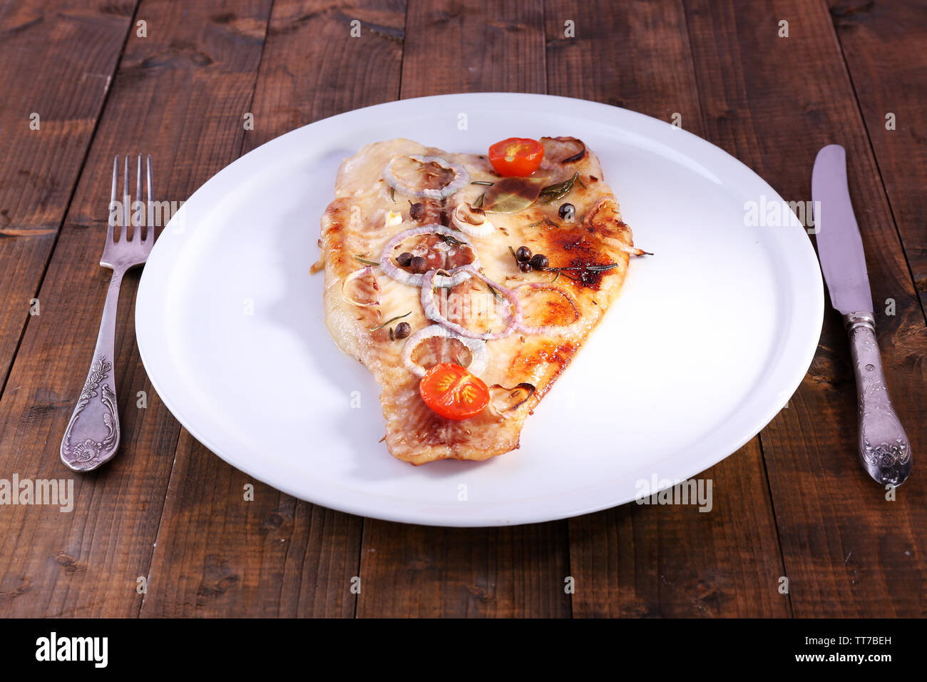 Dish of Pangasius fillet with spices and vegetables on plate and wooden ...