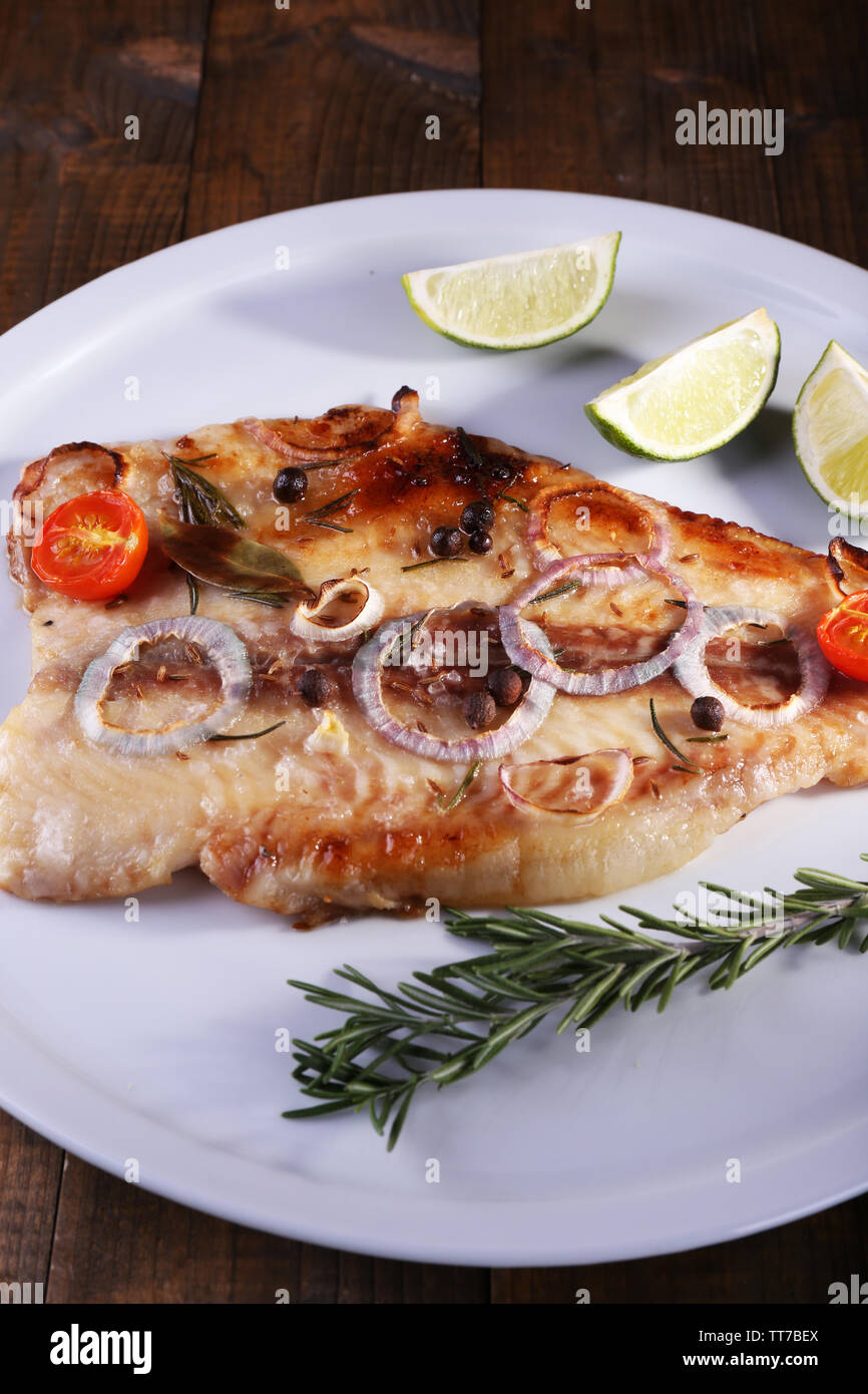 Dish of Pangasius fillet with spices and vegetables on plate and wooden ...