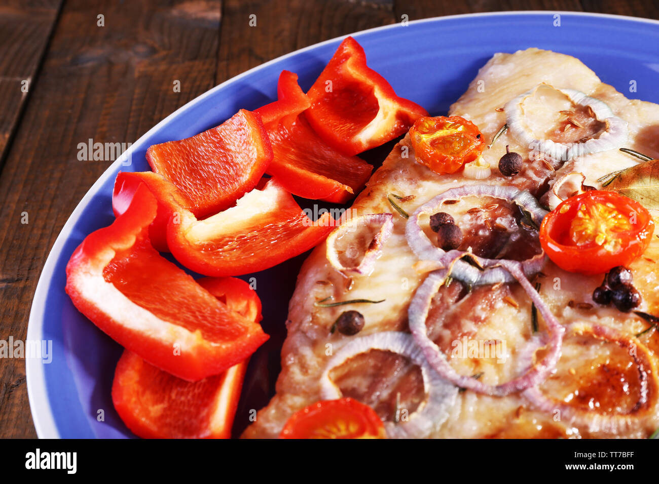 Dish of Pangasius fillet with spices and vegetables on wooden table ...