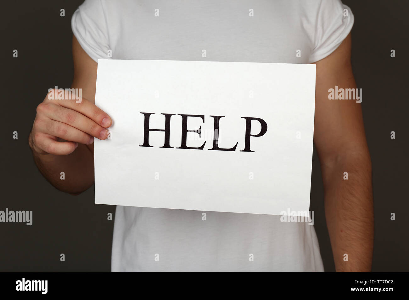 Sheet of paper with Help sign in male hand on dark background Stock ...
