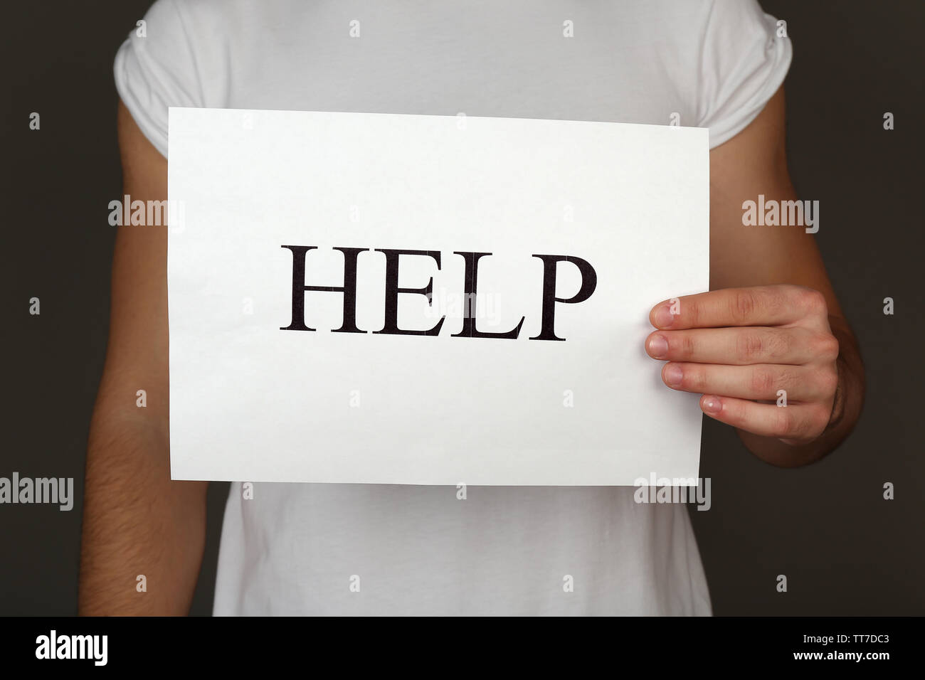 Sheet of paper with Help sign in male hand on dark background Stock ...