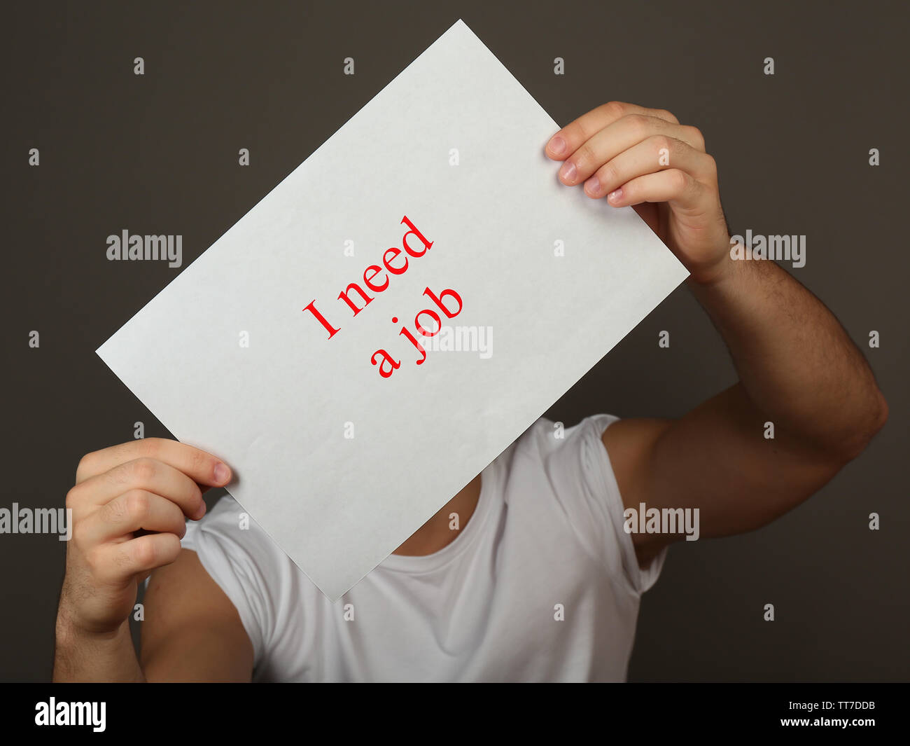 Sheet of paper with inscription I need a job in male hands on dark ...