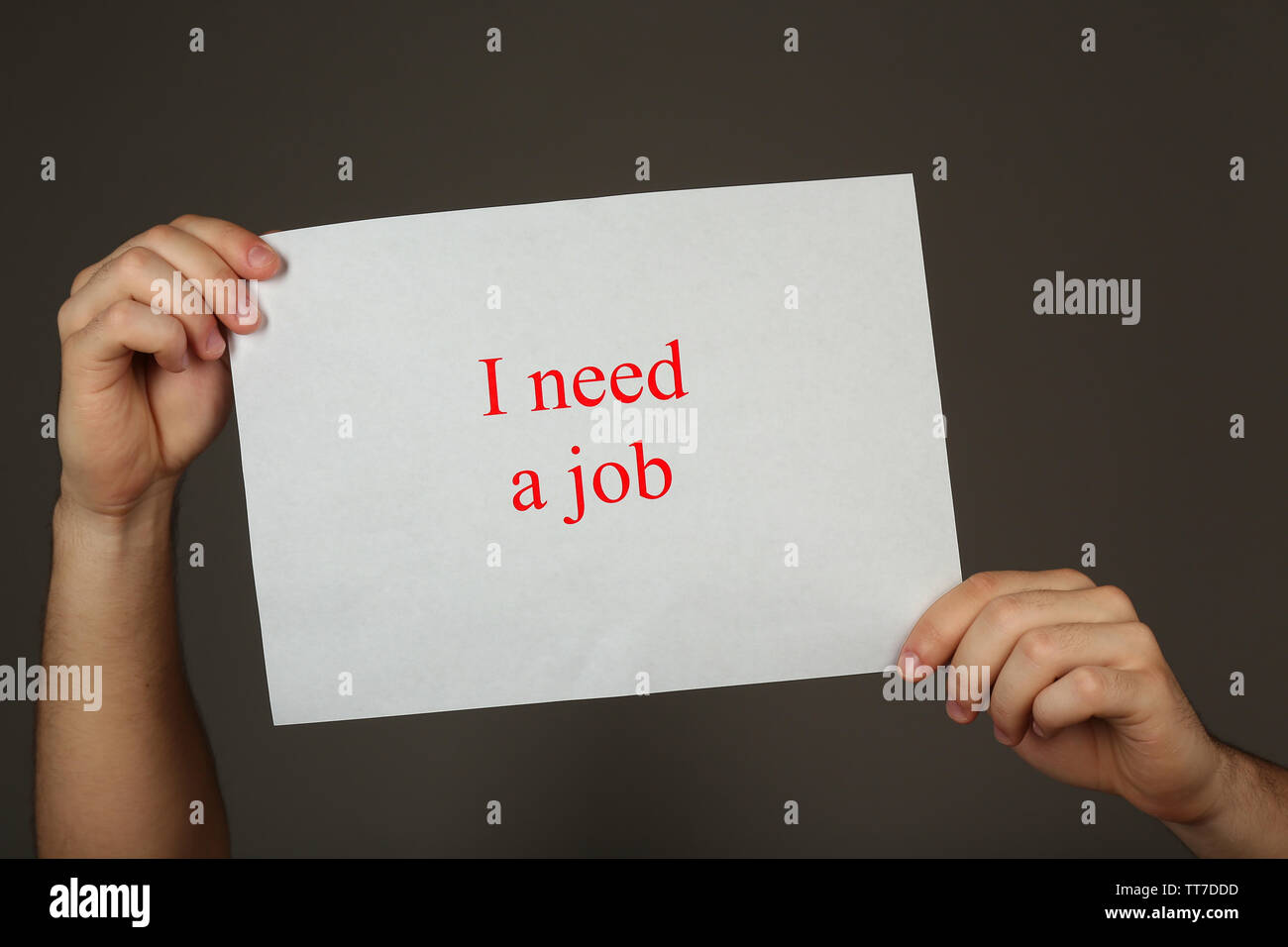 Sheet of paper with inscription I need a job in male hands on dark ...