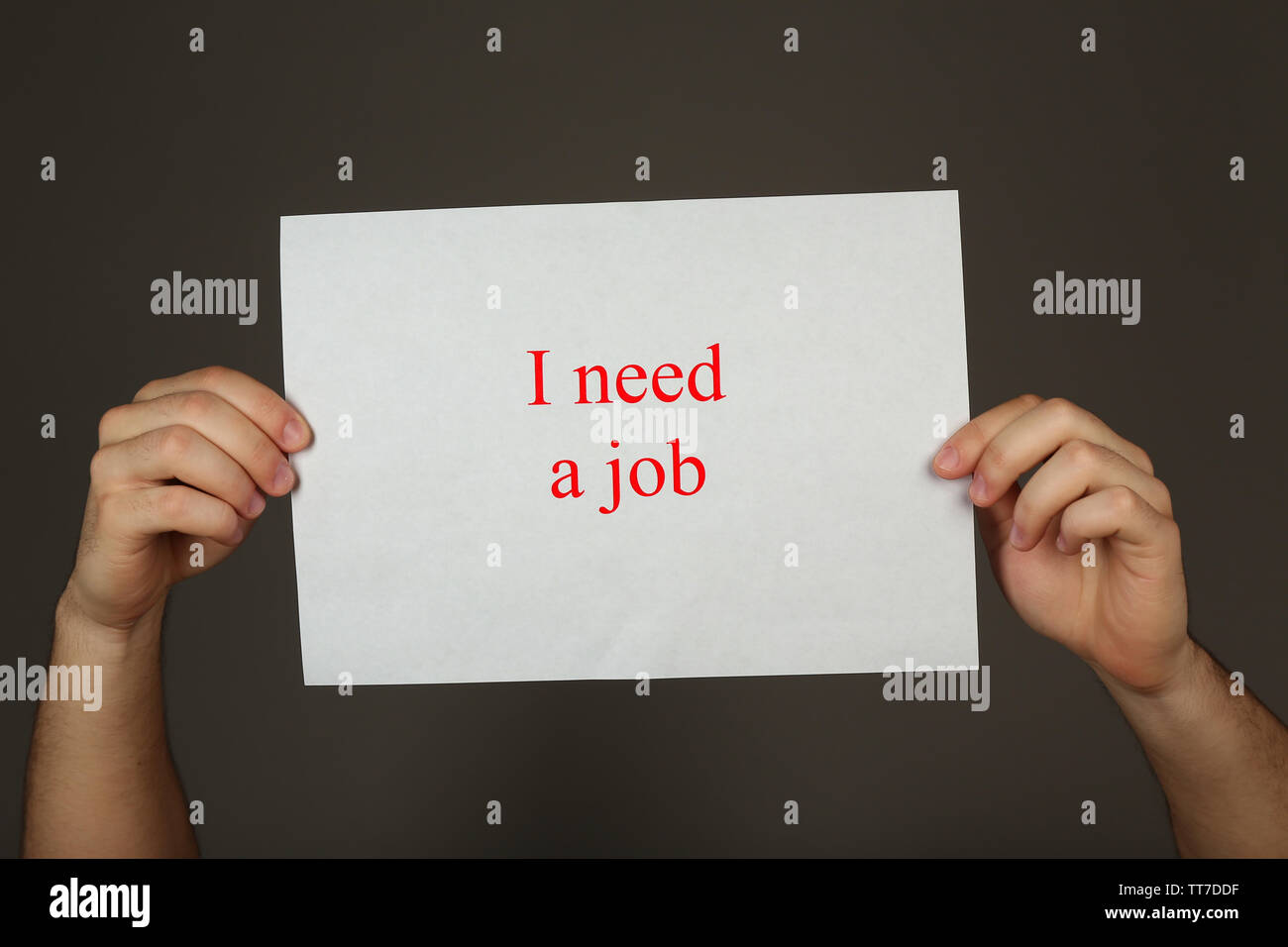 Sheet of paper with inscription I need a job in male hands on dark ...
