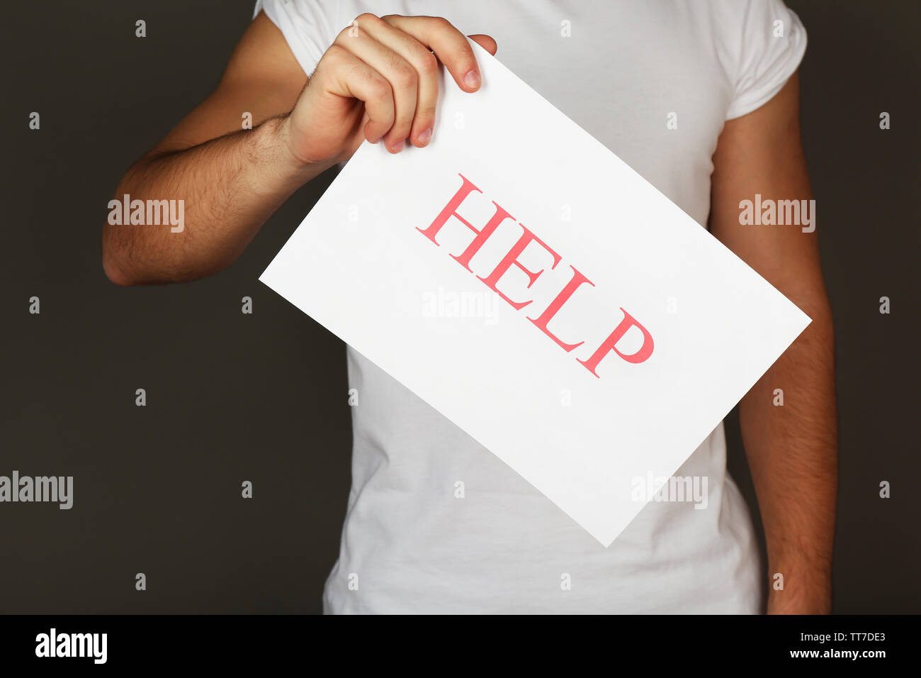 Sheet of paper with Help sign in male hand on dark background Stock ...