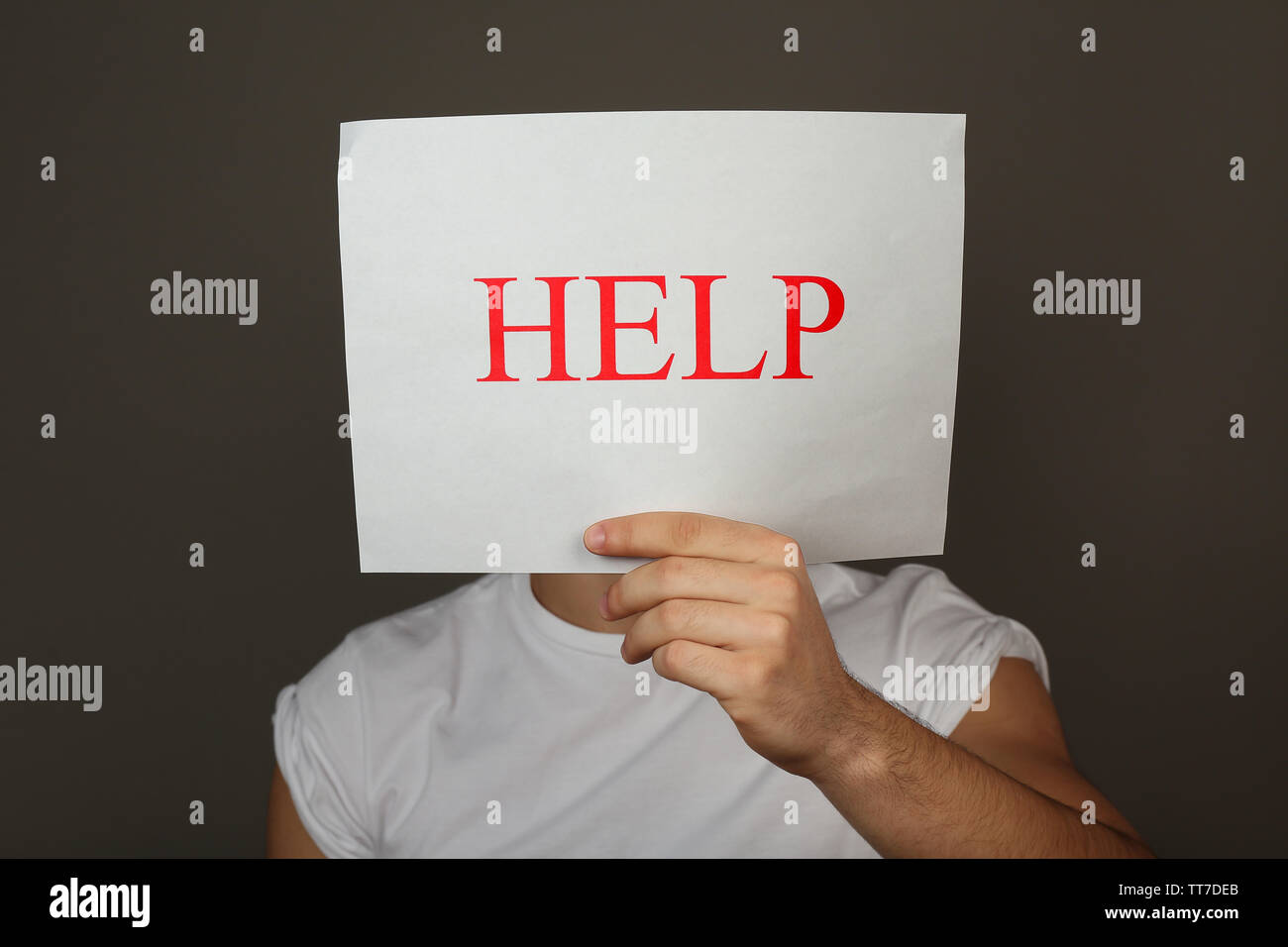 Sheet of paper with Help sign in male hand on dark background Stock ...