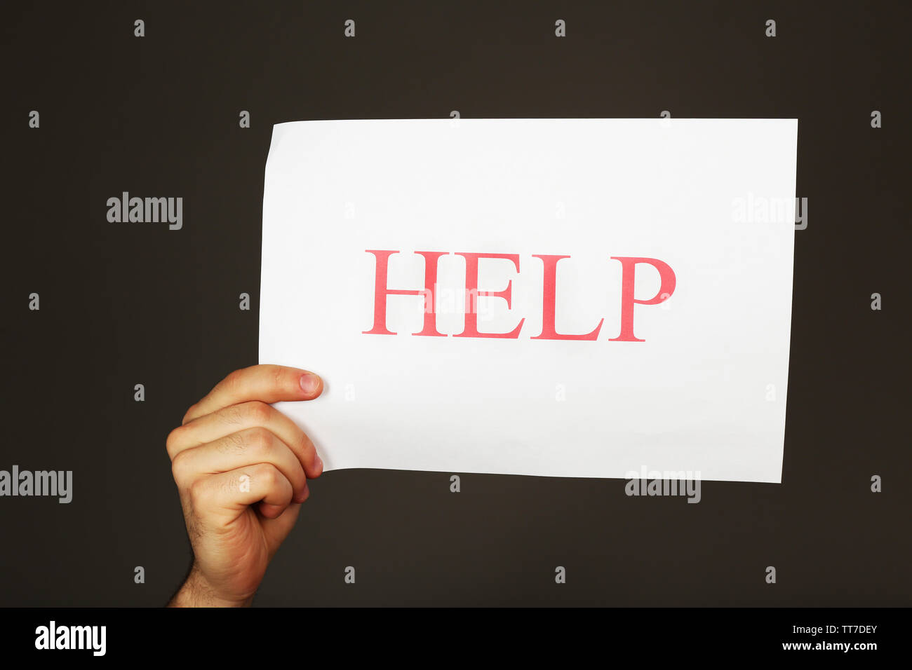 Sheet of paper with Help sign in male hand on dark background Stock ...