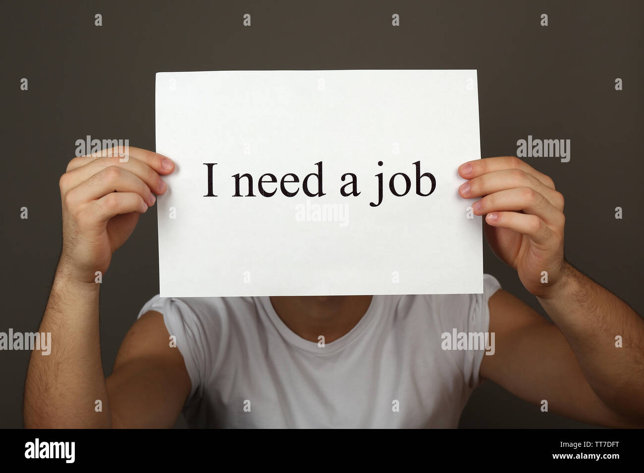 Sheet of paper with inscription I need a job in male hands on dark ...