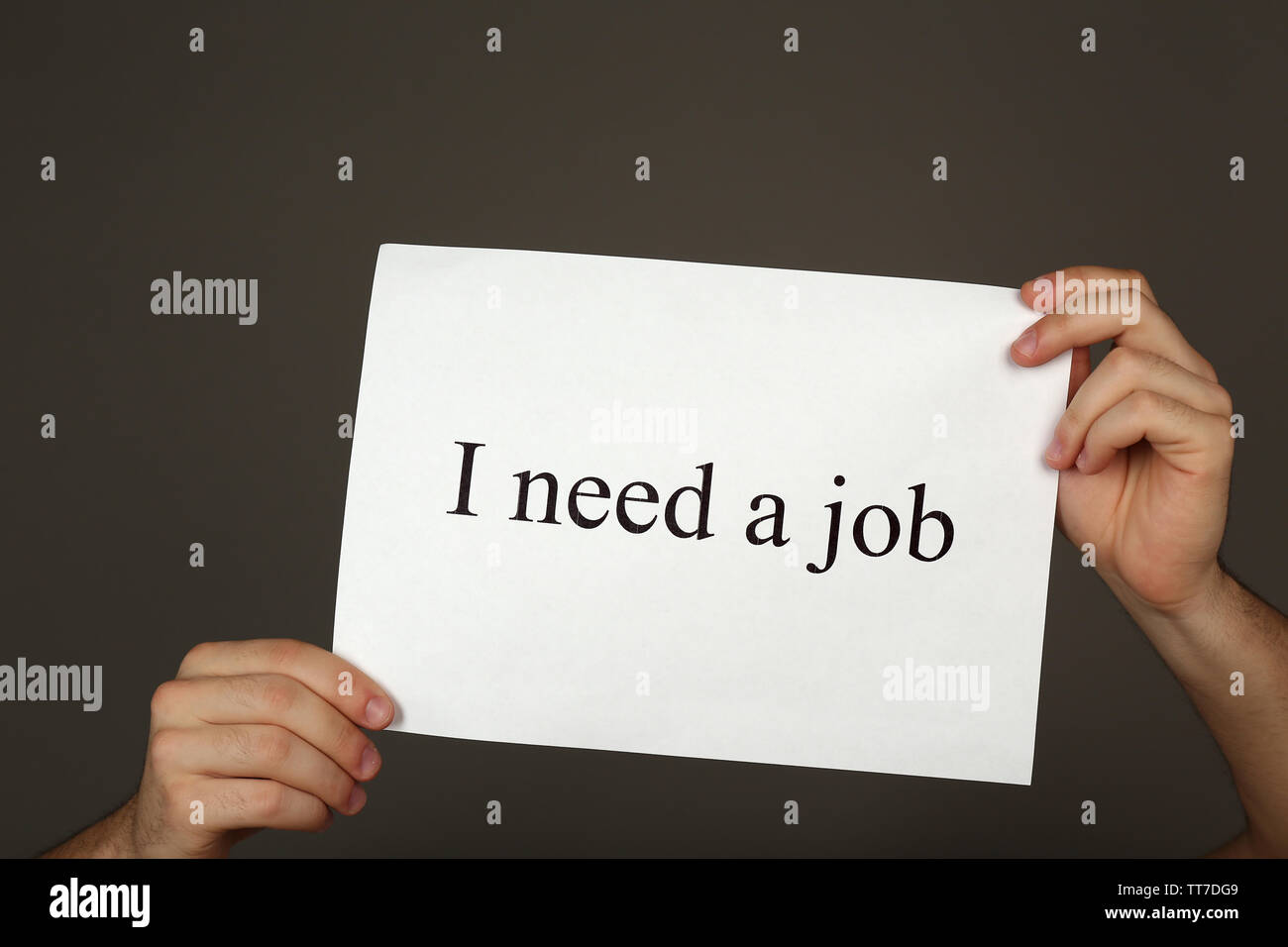 Sheet of paper with inscription I need a job in male hands on dark ...
