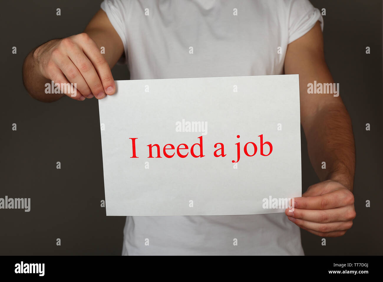 Sheet of paper with inscription I need a job in male hands on dark ...