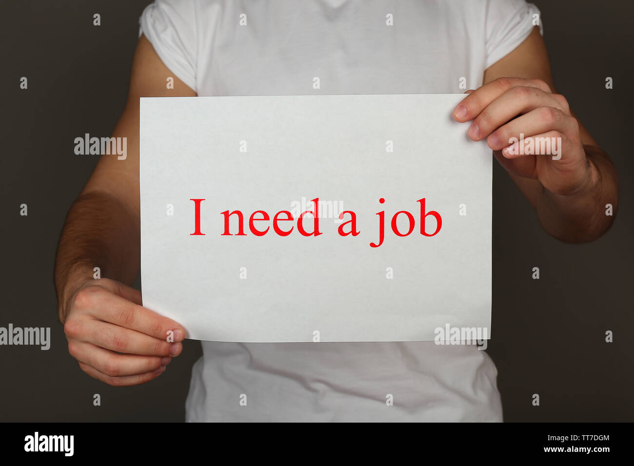 Sheet of paper with inscription I need a job in male hands on dark ...