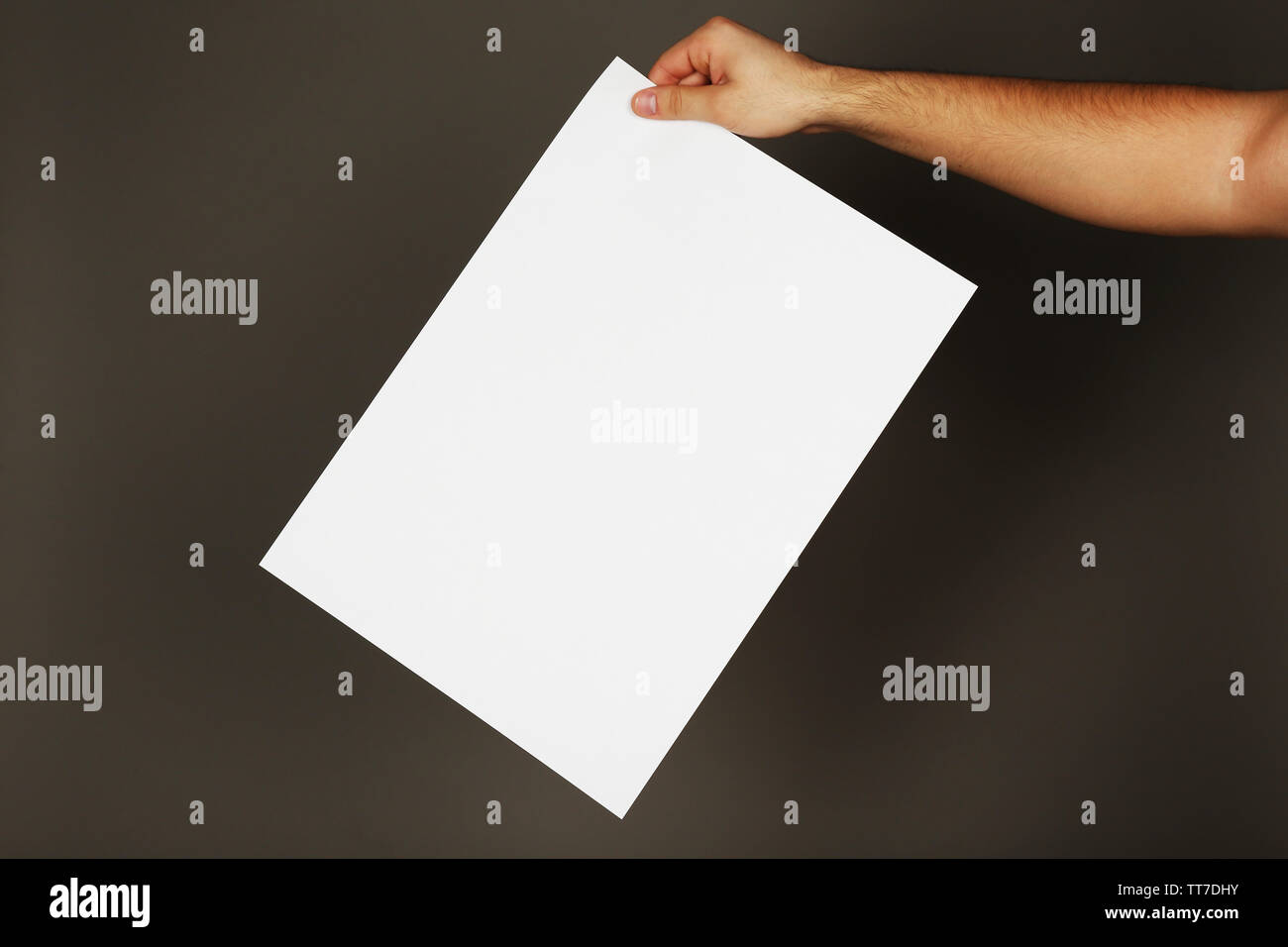 Blank sheet of paper in male hand on dark background Stock Photo - Alamy