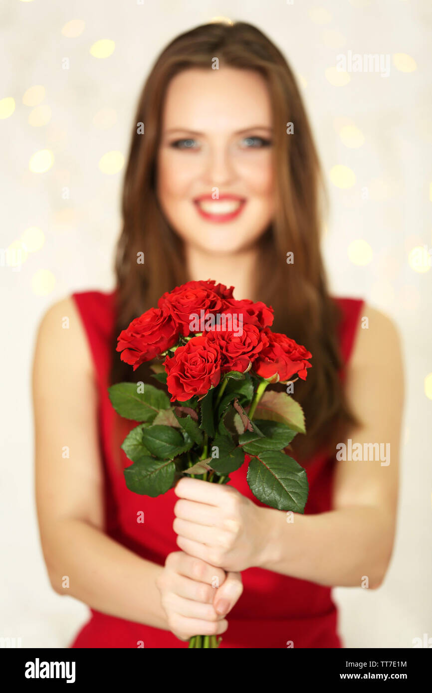 Smiling girl with bouquet of red roses on lights background Stock Photo ...