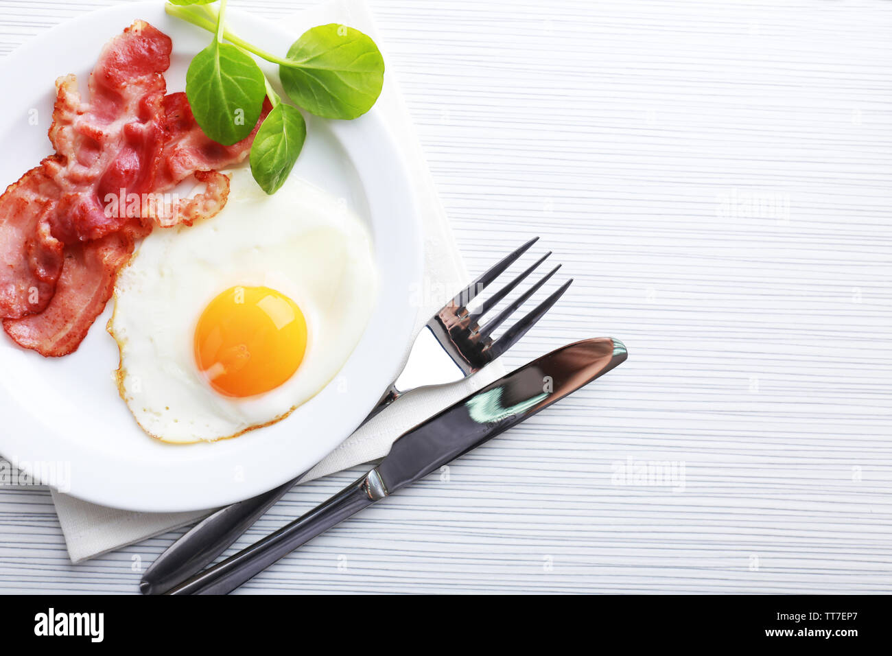 Bacon and eggs on color wooden table background Stock Photo - Alamy