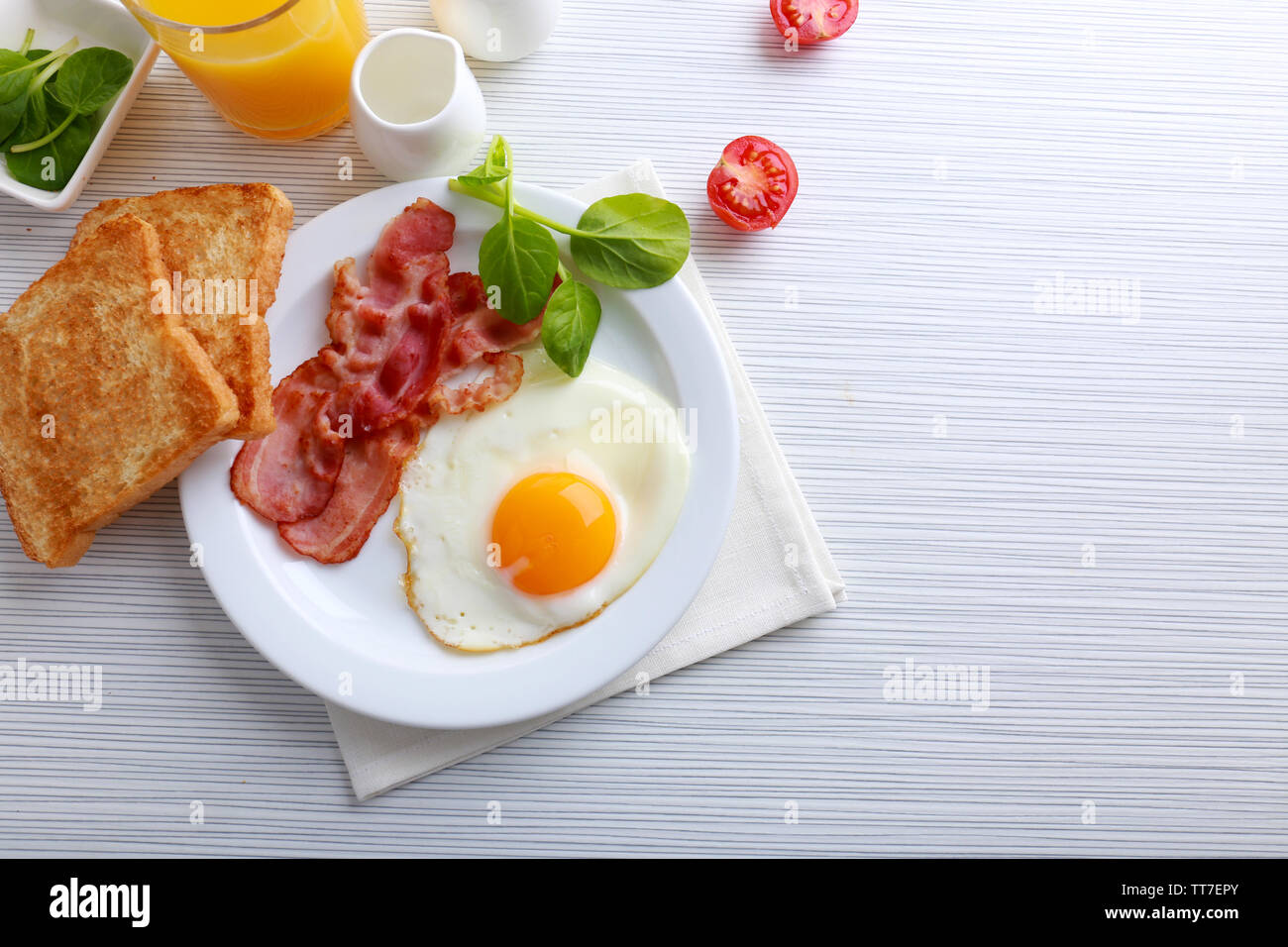Bacon and eggs on color wooden table background Stock Photo - Alamy