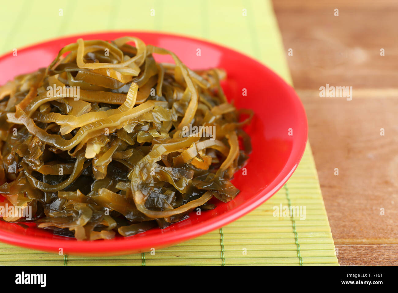 Seaweed in red plat on bamboo mat and wooden table background Stock ...