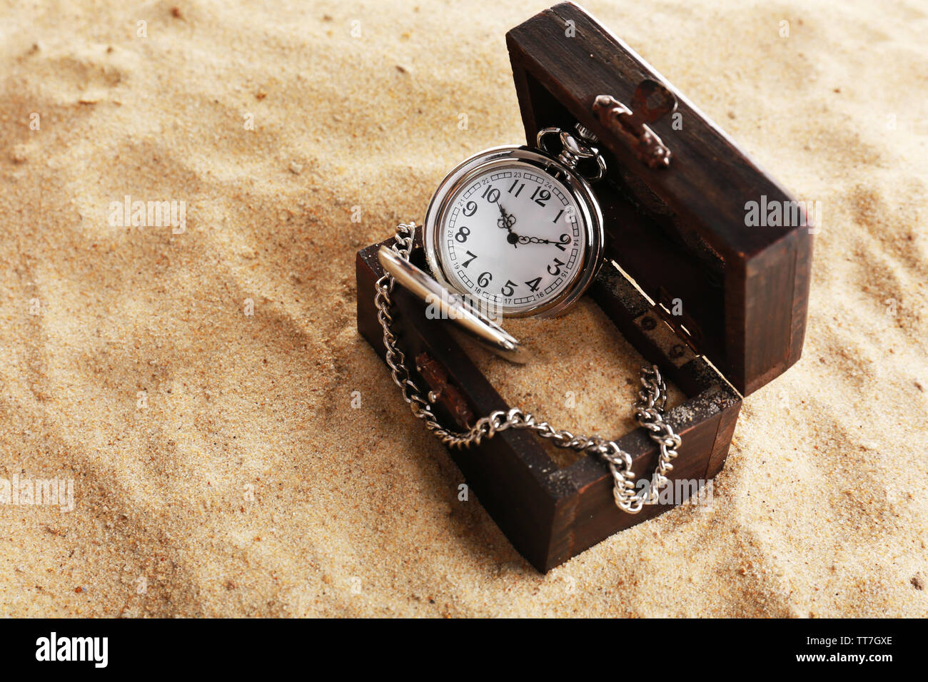 Silver pocket clock on sand background Stock Photo - Alamy