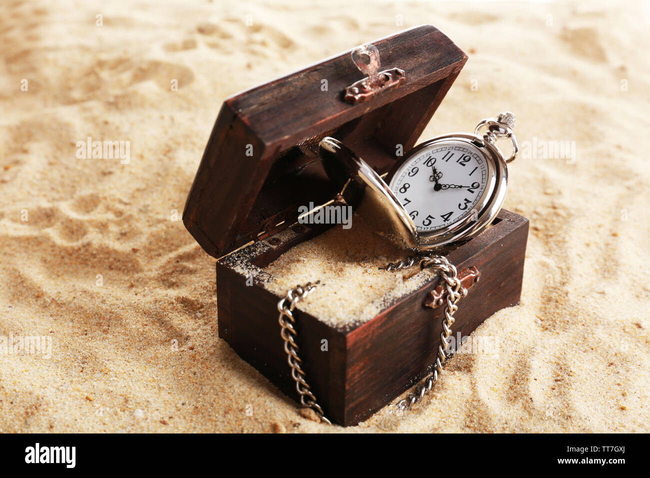 Silver pocket clock on sand background Stock Photo - Alamy