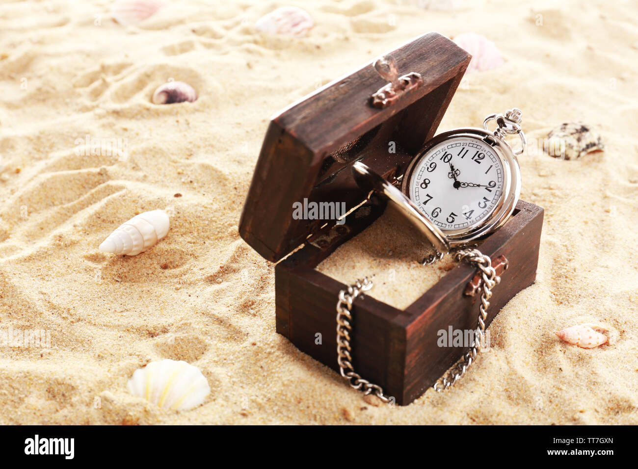 Silver pocket clock on sand background Stock Photo - Alamy