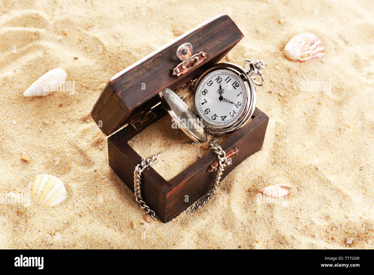 Silver pocket clock on sand background Stock Photo - Alamy