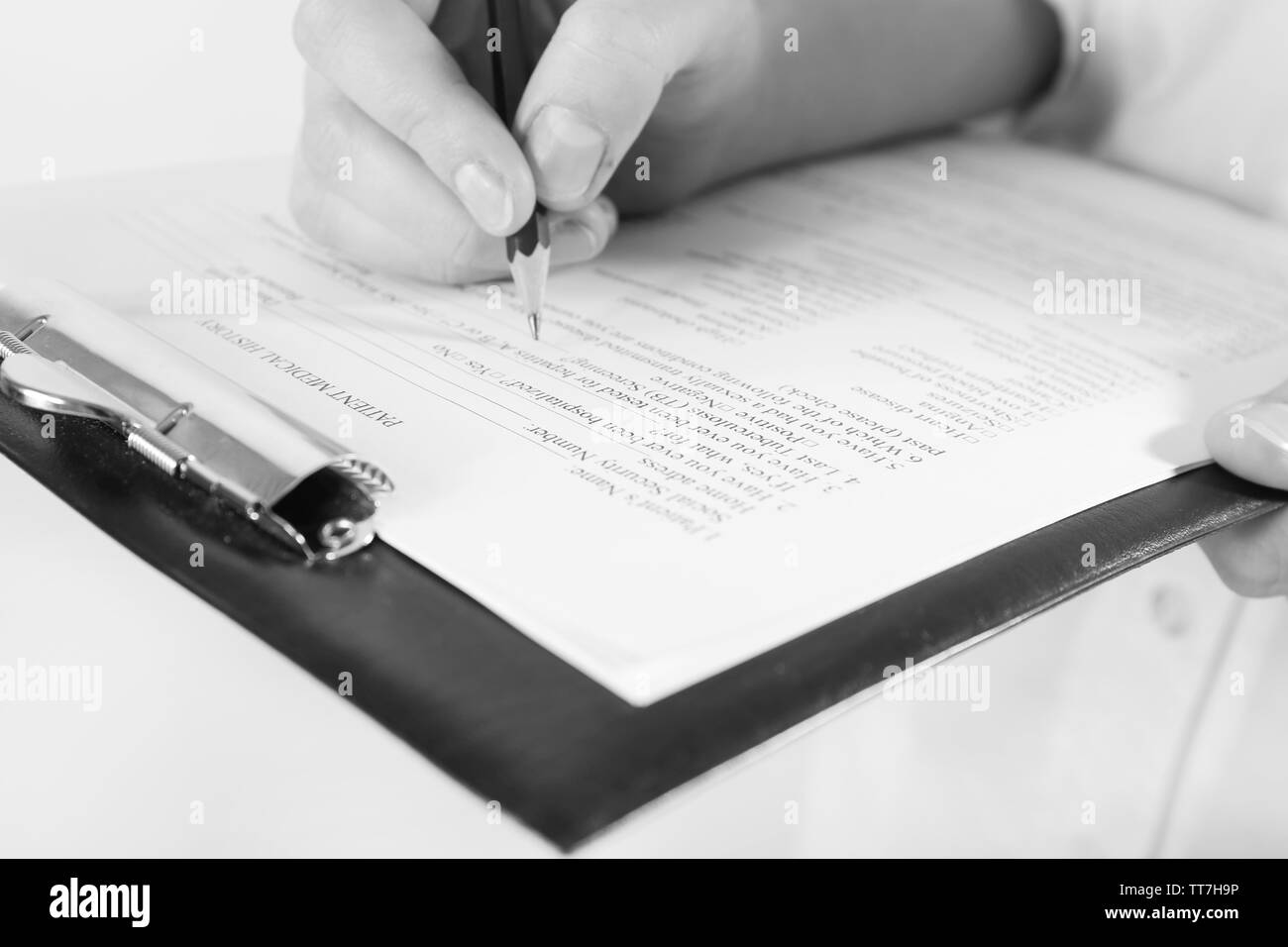 Doctor writing on clipboard on light background Stock Photo - Alamy