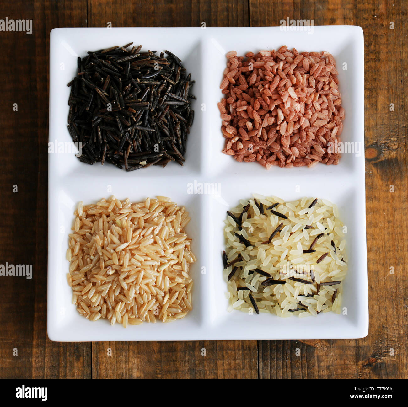 Different types of rice on plate on wooden background Stock Photo - Alamy