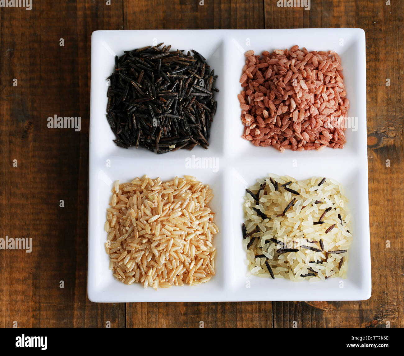 Different types of rice on plate on wooden background Stock Photo - Alamy