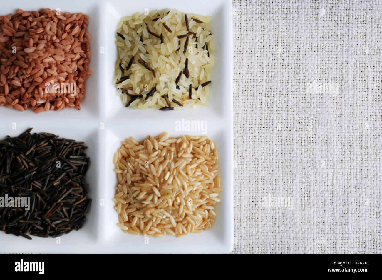 Different types of rice on plate on fabric background Stock Photo - Alamy