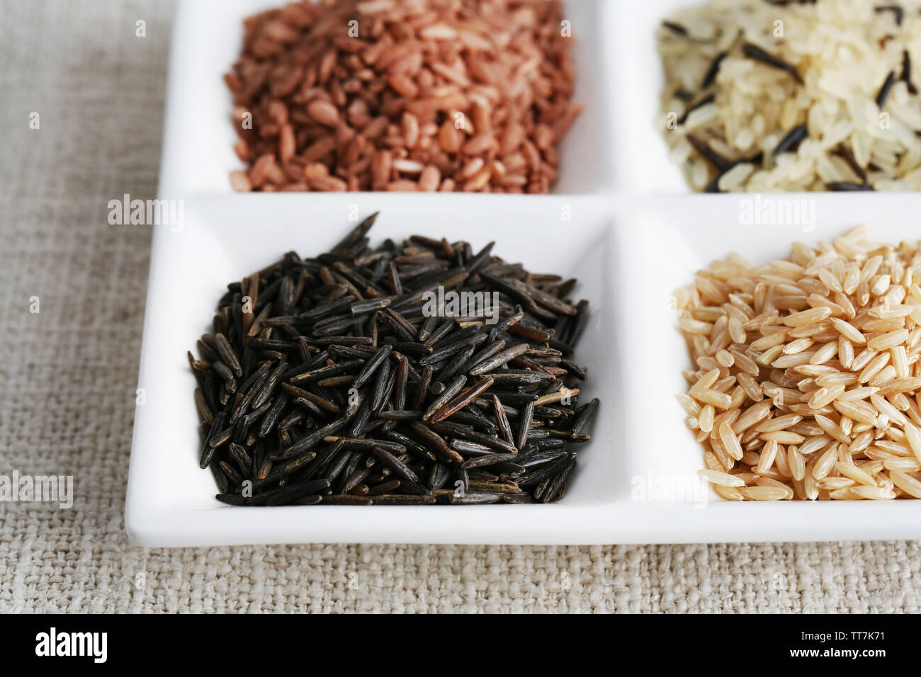 Different types of rice on plate on fabric background Stock Photo - Alamy