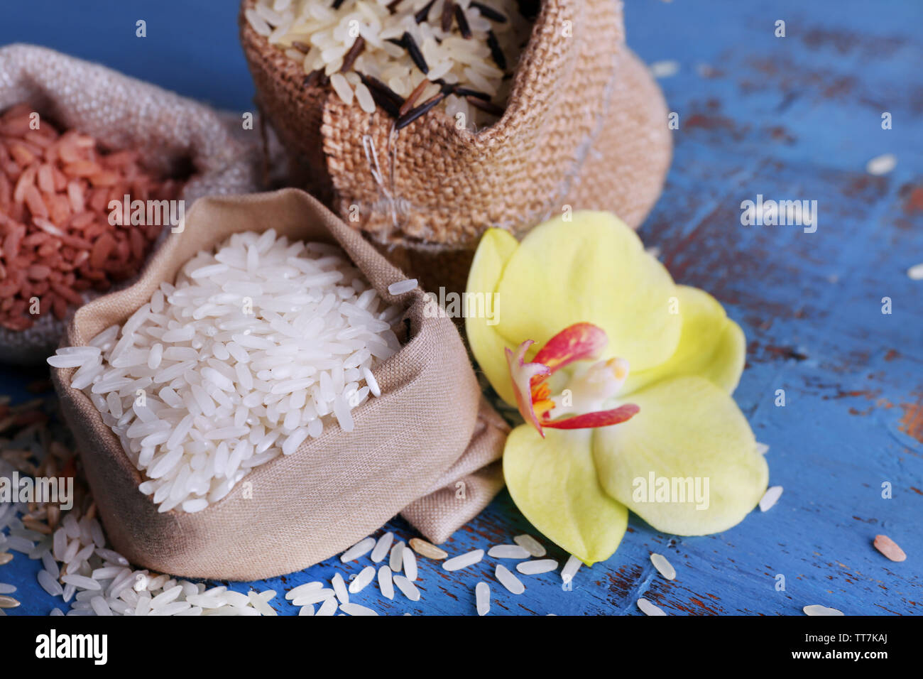 Different types of rice in sacks on wooden background Stock Photo - Alamy