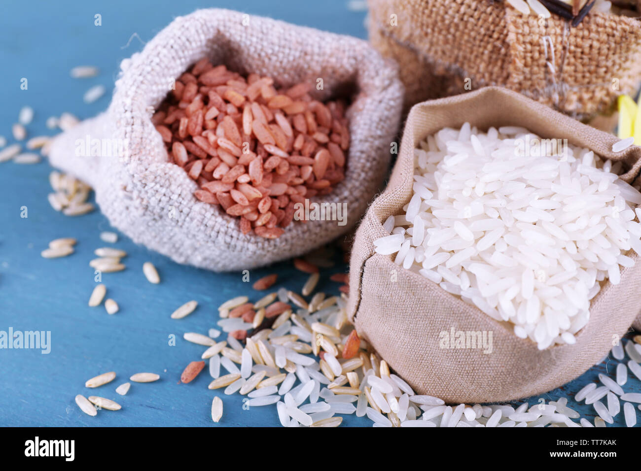 Different types of rice in sacks on wooden background Stock Photo - Alamy