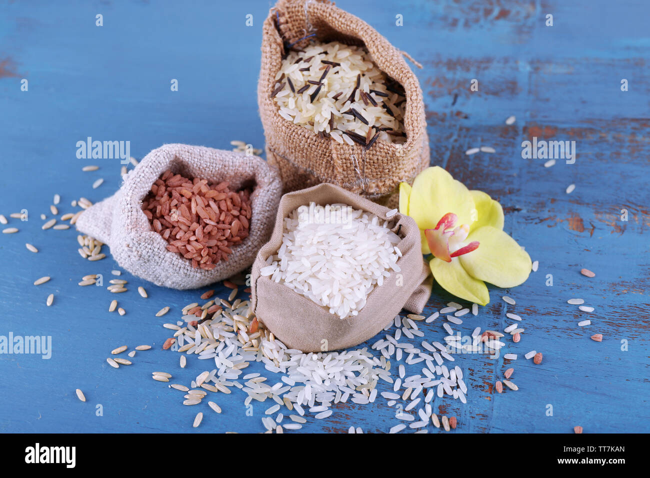 Different types of rice in sacks on wooden background Stock Photo - Alamy