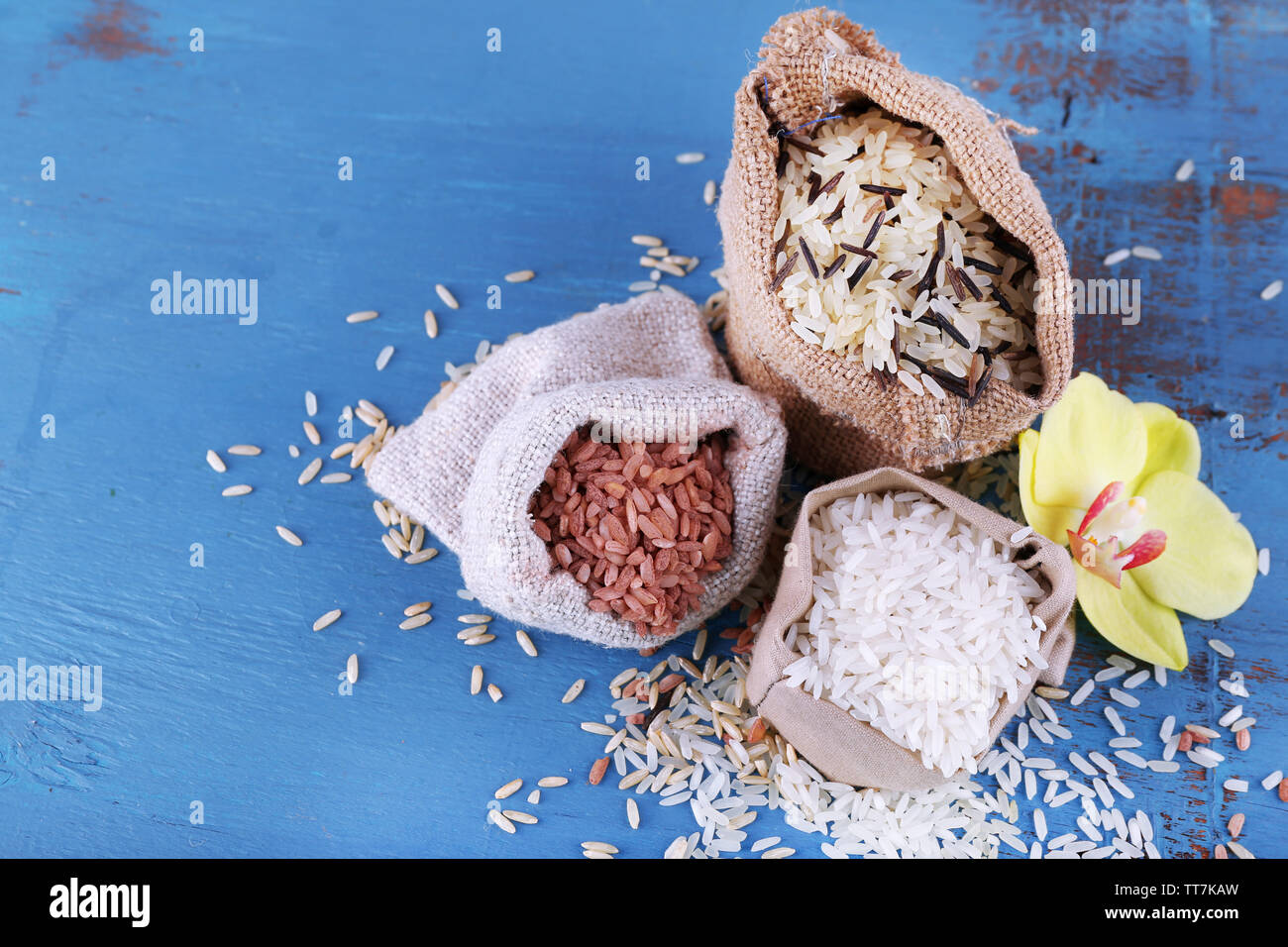 Different types of rice in sacks on wooden background Stock Photo - Alamy