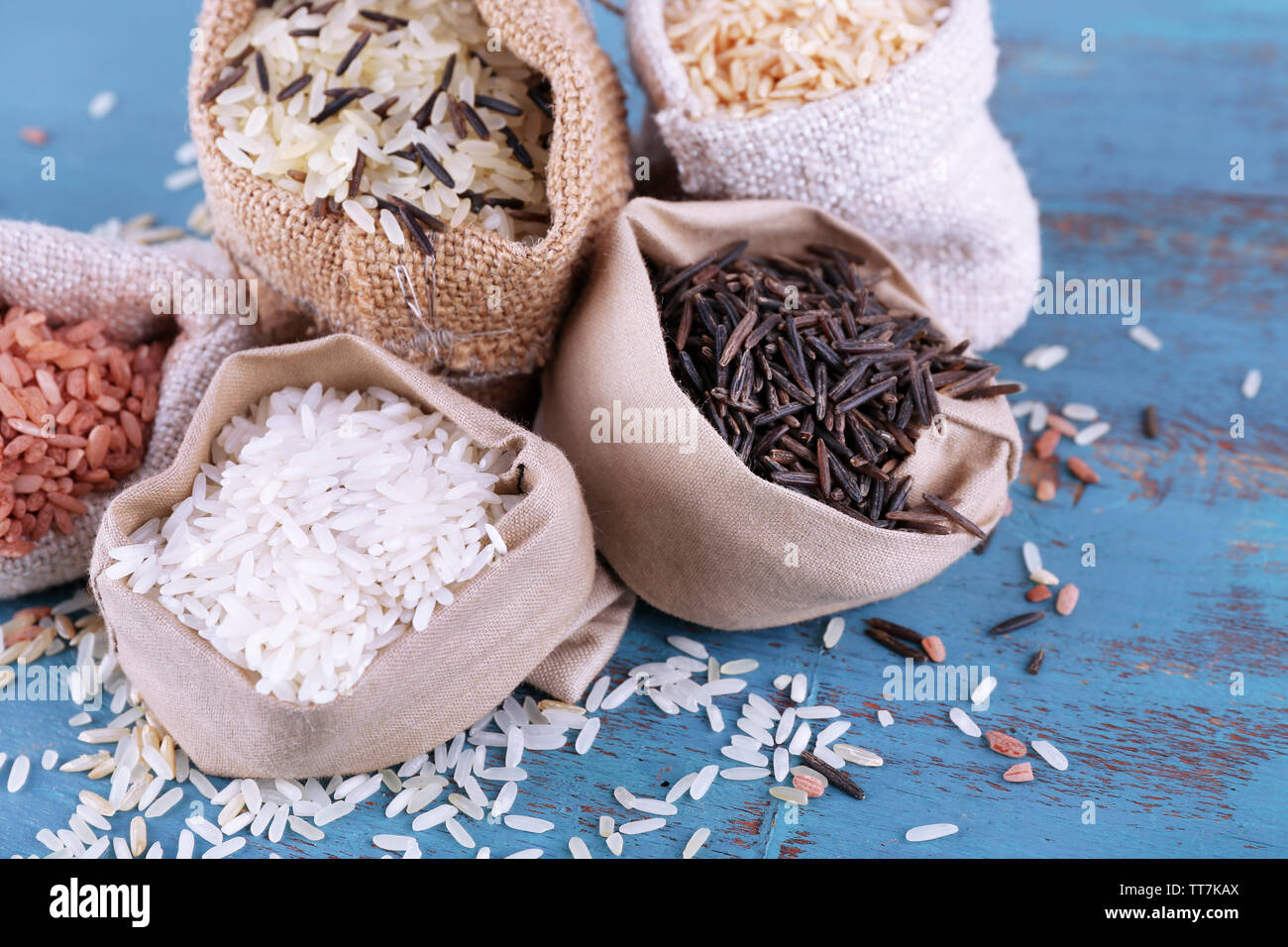 Different types of rice in sacks on wooden background Stock Photo - Alamy