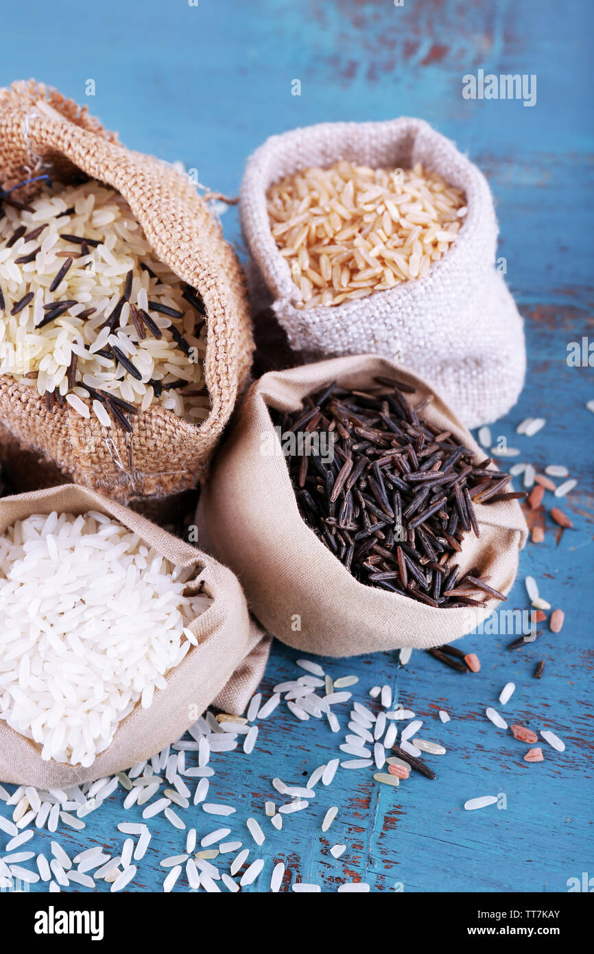 Different types of rice in sacks on wooden background Stock Photo - Alamy