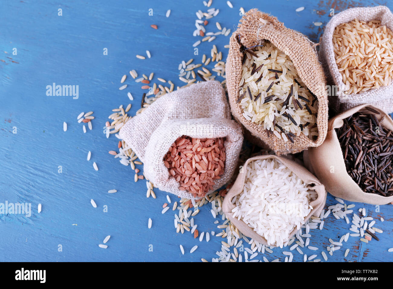 Different types of rice in sacks on wooden background Stock Photo - Alamy